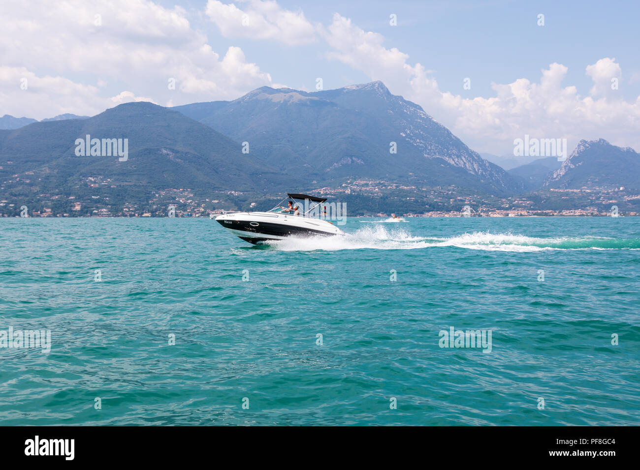 Fast speedboat on Lake Garda in front of mountains. The powerboat has a ...