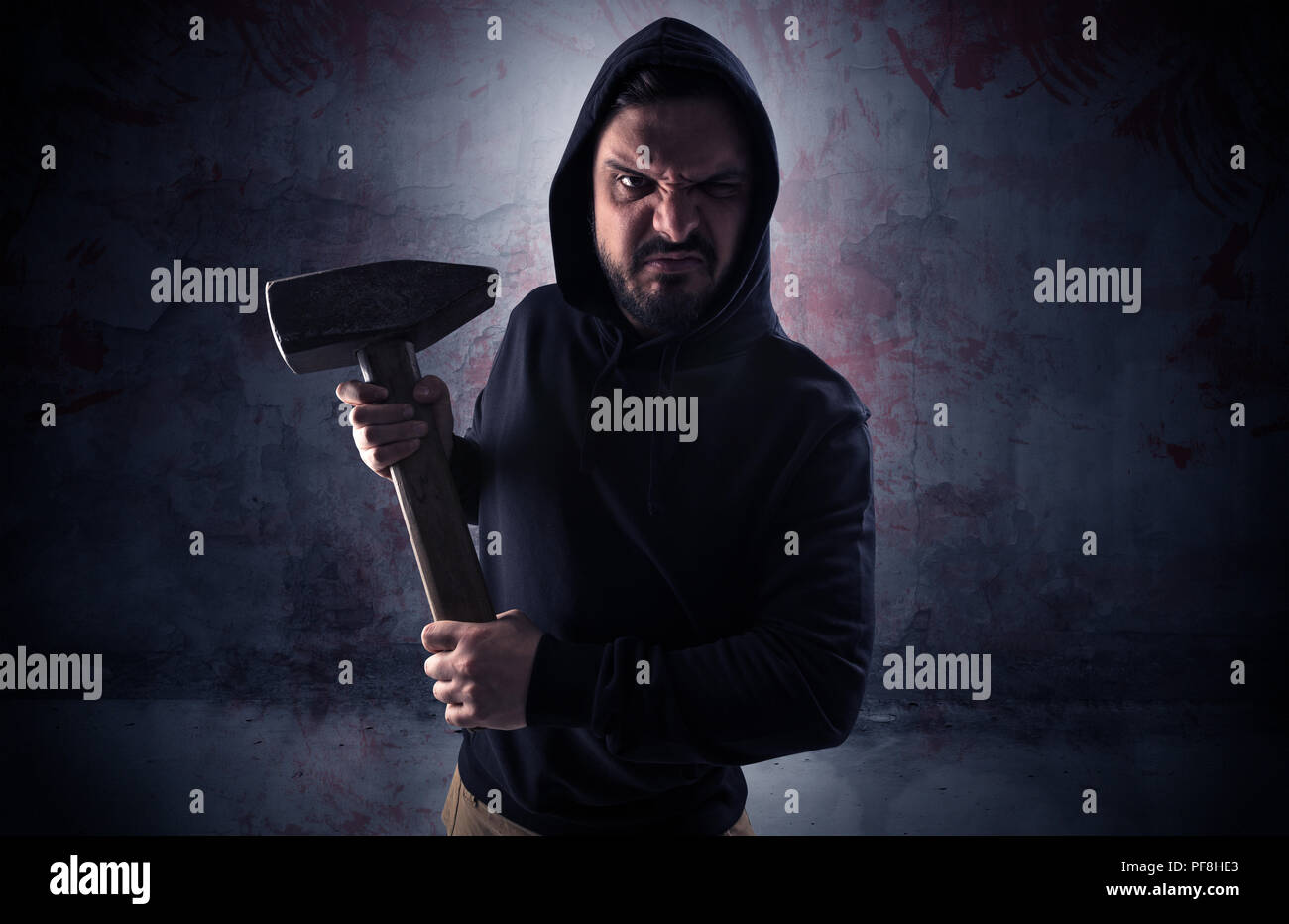 Armed rude assassin in an empty bloody room concept with gun ax ...