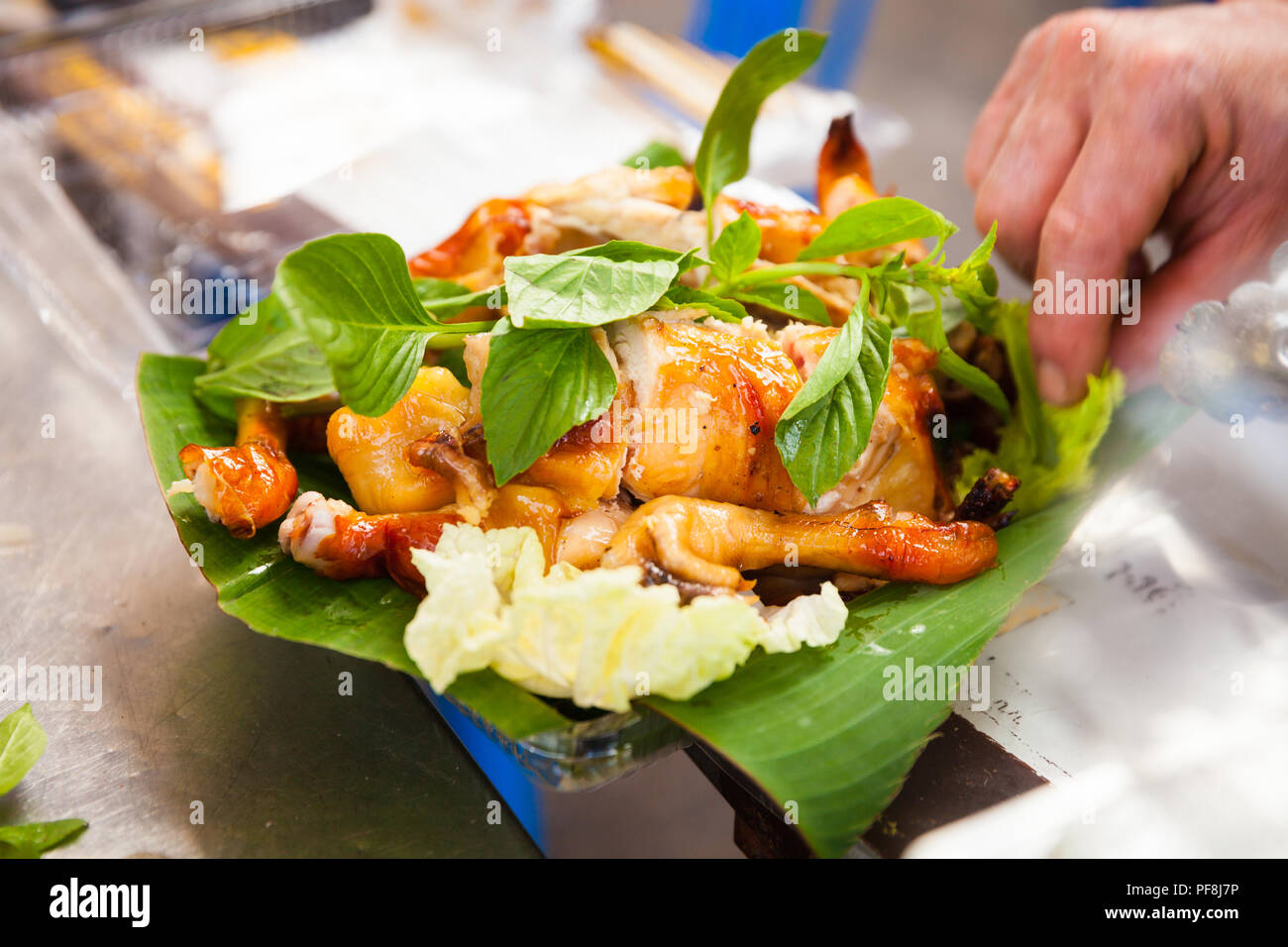 Enthusiastic street cook prepares a delicious chicken in outdoor market ...