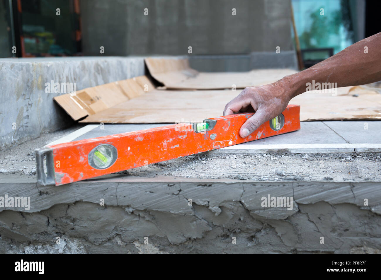 Exterior worker using level for laying cement floor Stock Photo - Alamy