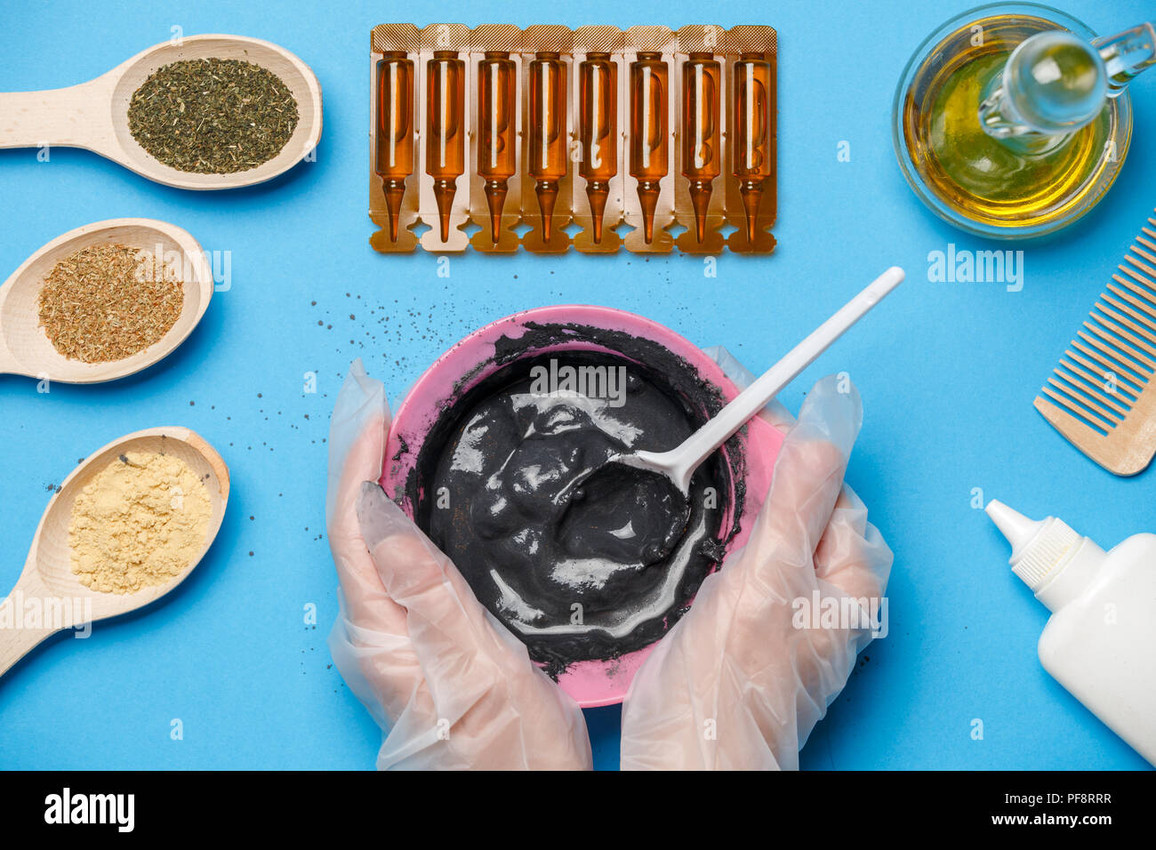 Photo from above with pink cup with black clay, mask oil, wooden spoons ...