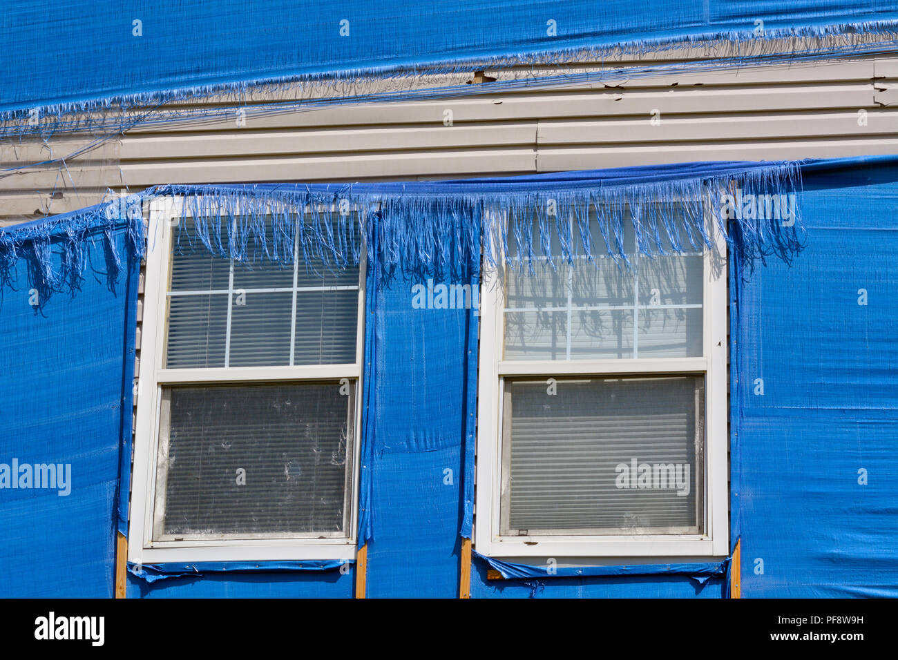 Detail of hail storm damaged home protected by blue tarp weathered and ...