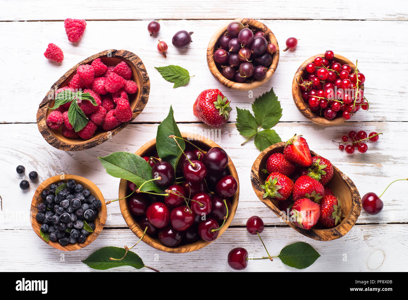 Berry mix in wooden bowls on white. Cherry strawberry raspberry currant ...