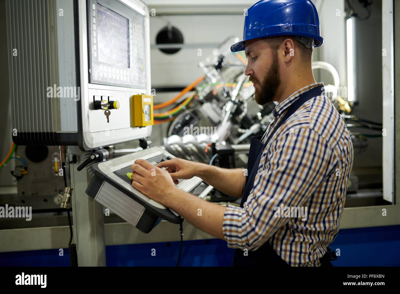 Side view portrait of machine operator wearing hardhat sitting at ...