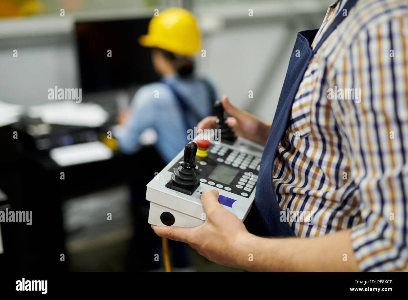 Mid section shot of unrecognizable factory worker operating machine ...