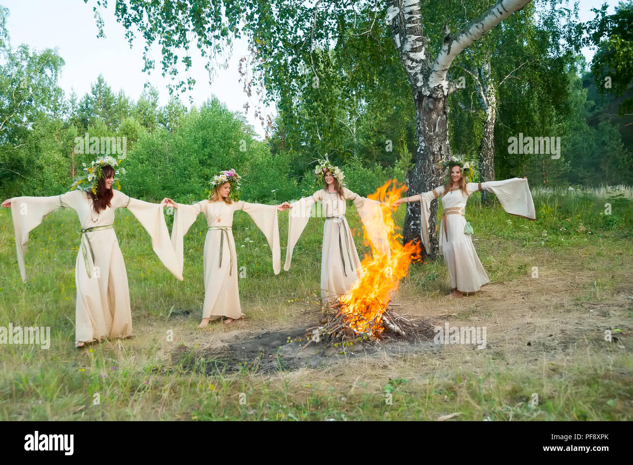 Four attractive Women with Wreath of Flowers dancing around bonfire ...
