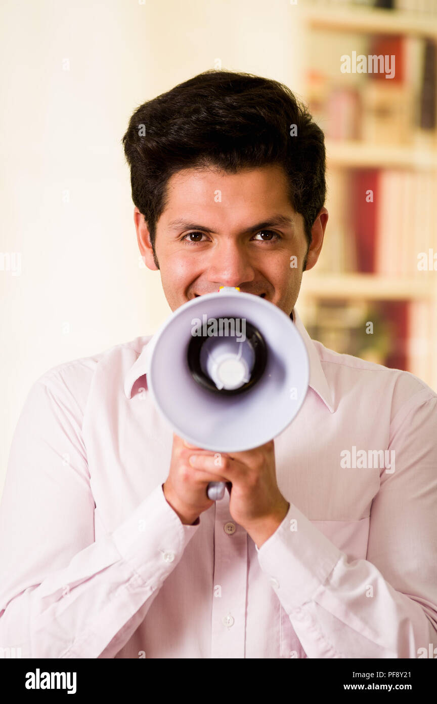 Portrait of a smiling handsome man talking with a megaphone in a ...
