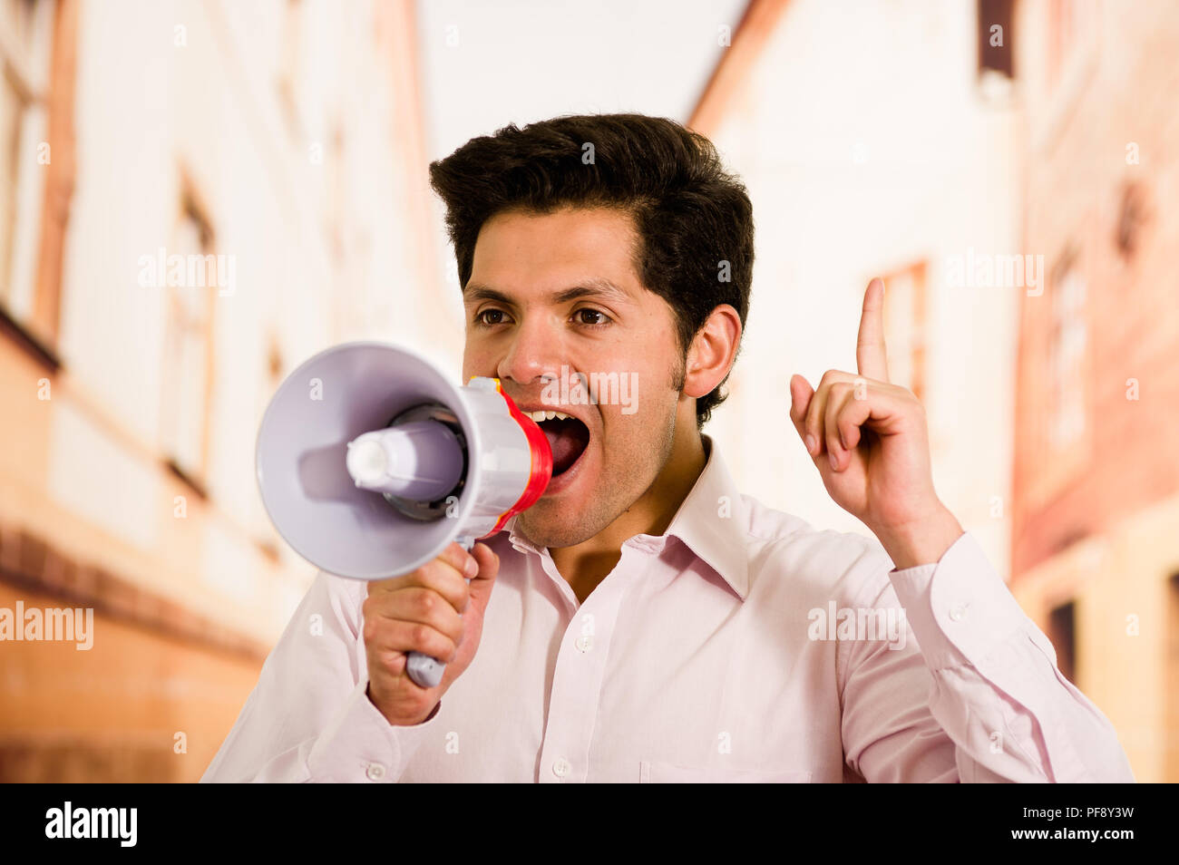 Close up of a handsome man screaming with a megaphone, doing a signal ...