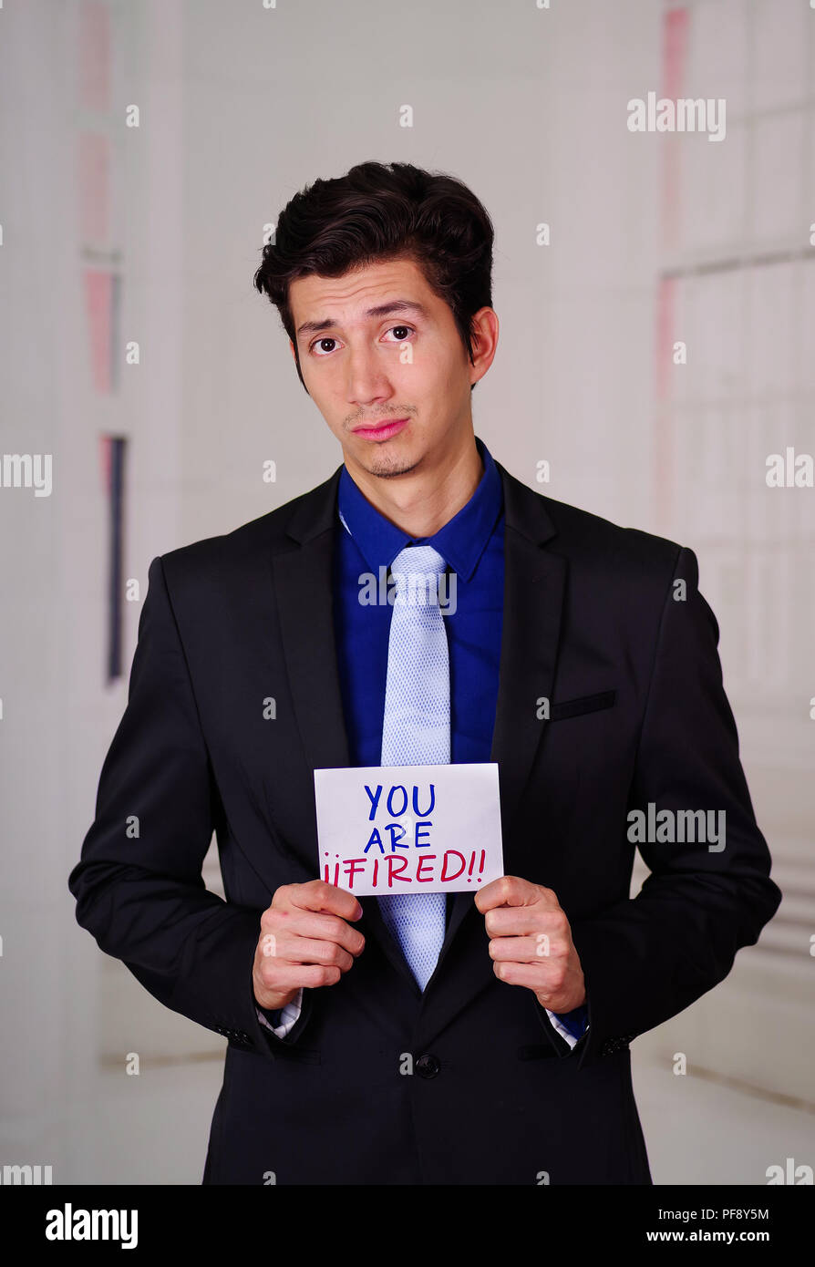 Sad business man hold paper you're fired text on it, in a blurred ...