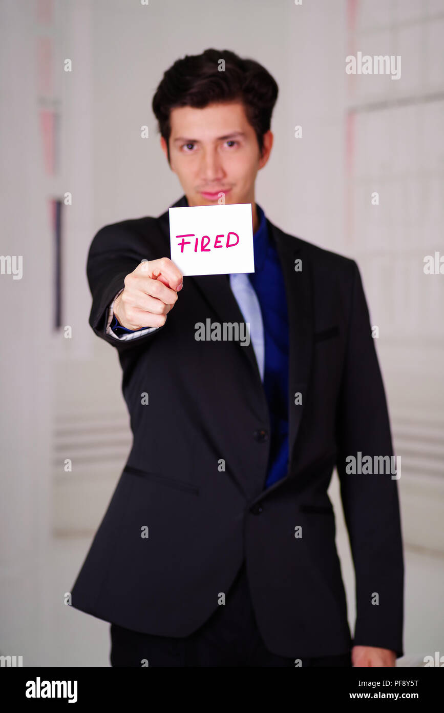 Sad business man holding a paper of fired text on it in his hand, in a ...