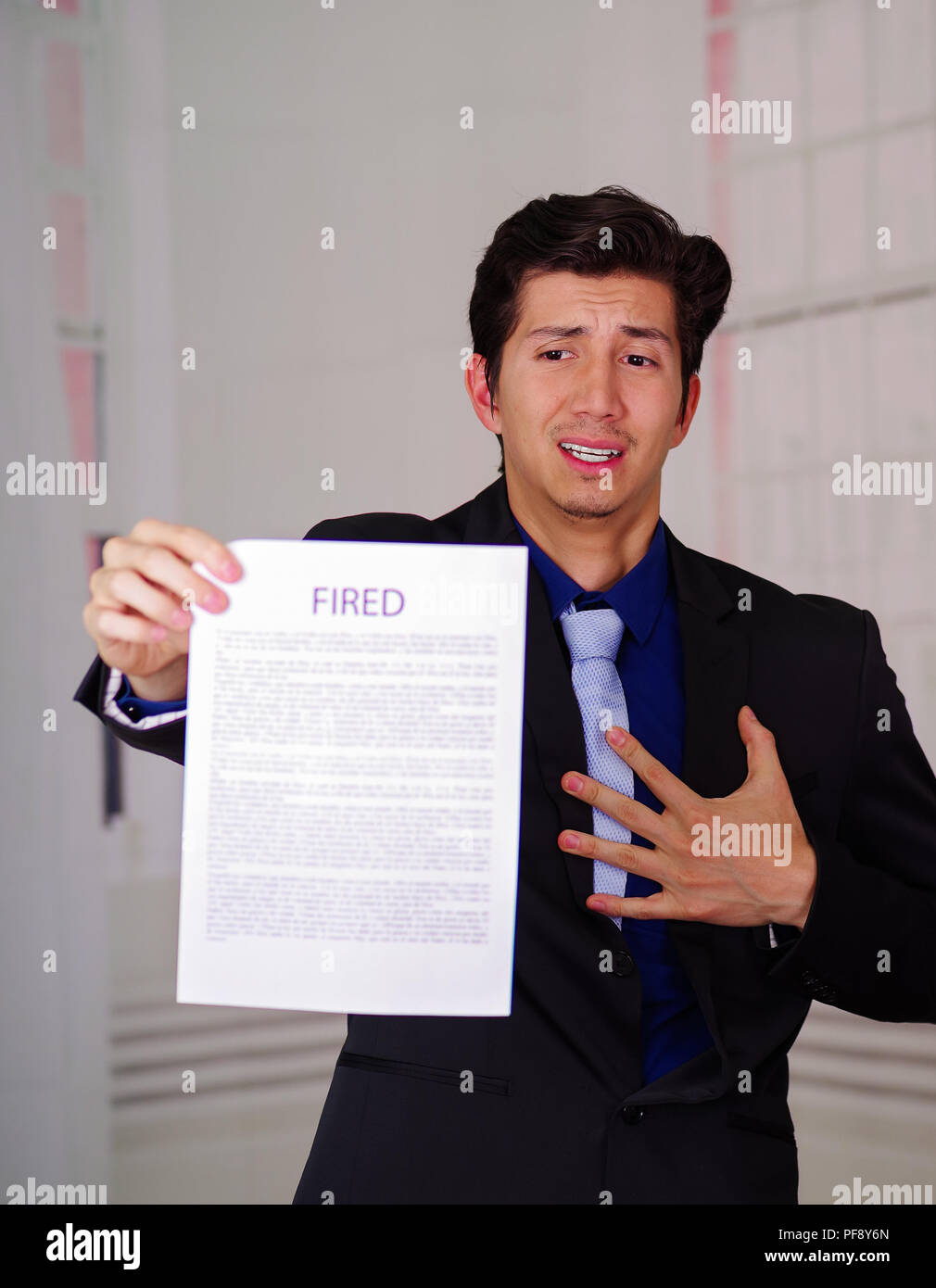 Close up of surprised young businessman wearing a suit and holding a ...