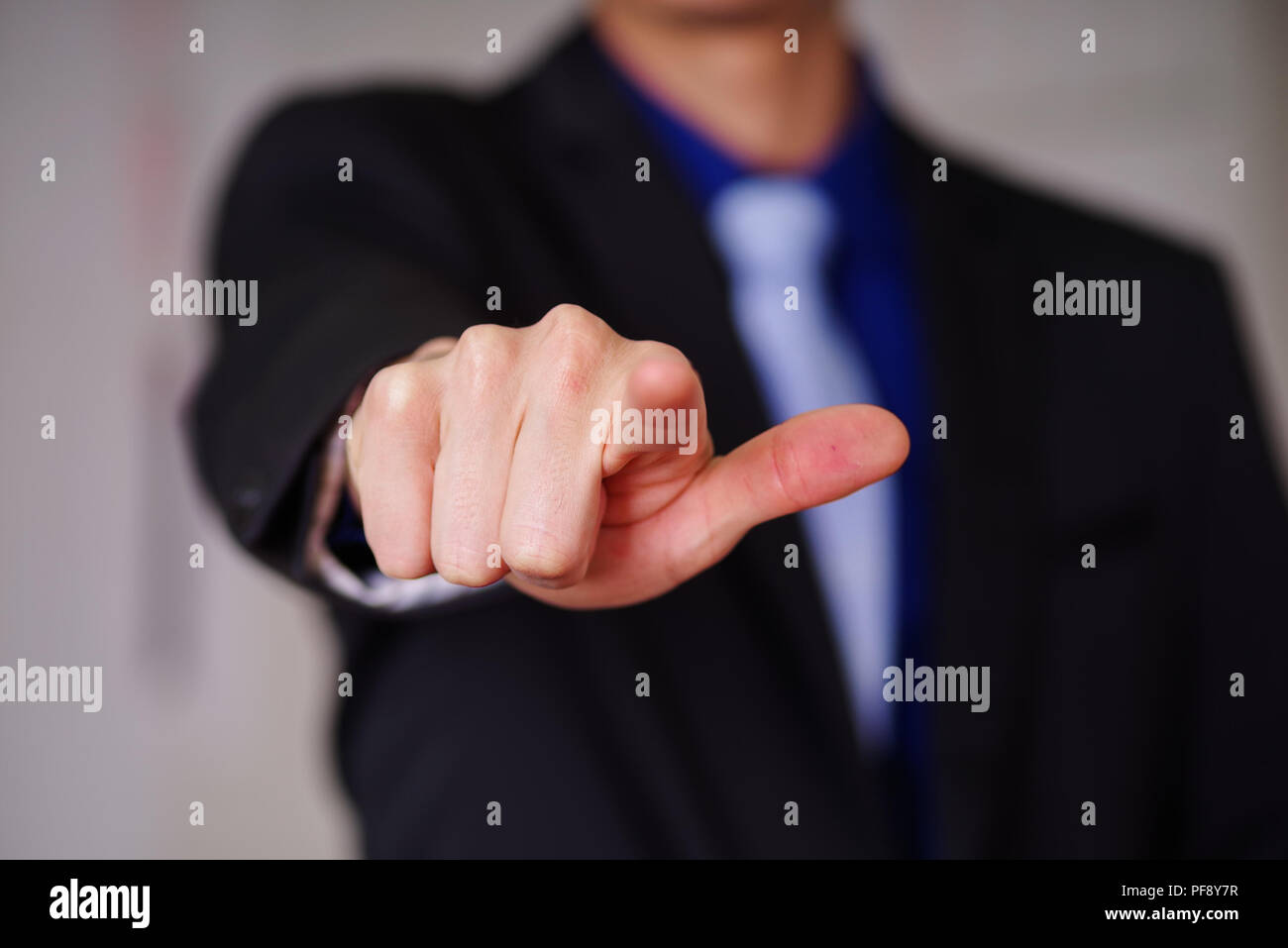 Close up of man wearing a suit, with an open hand pointing in front of ...