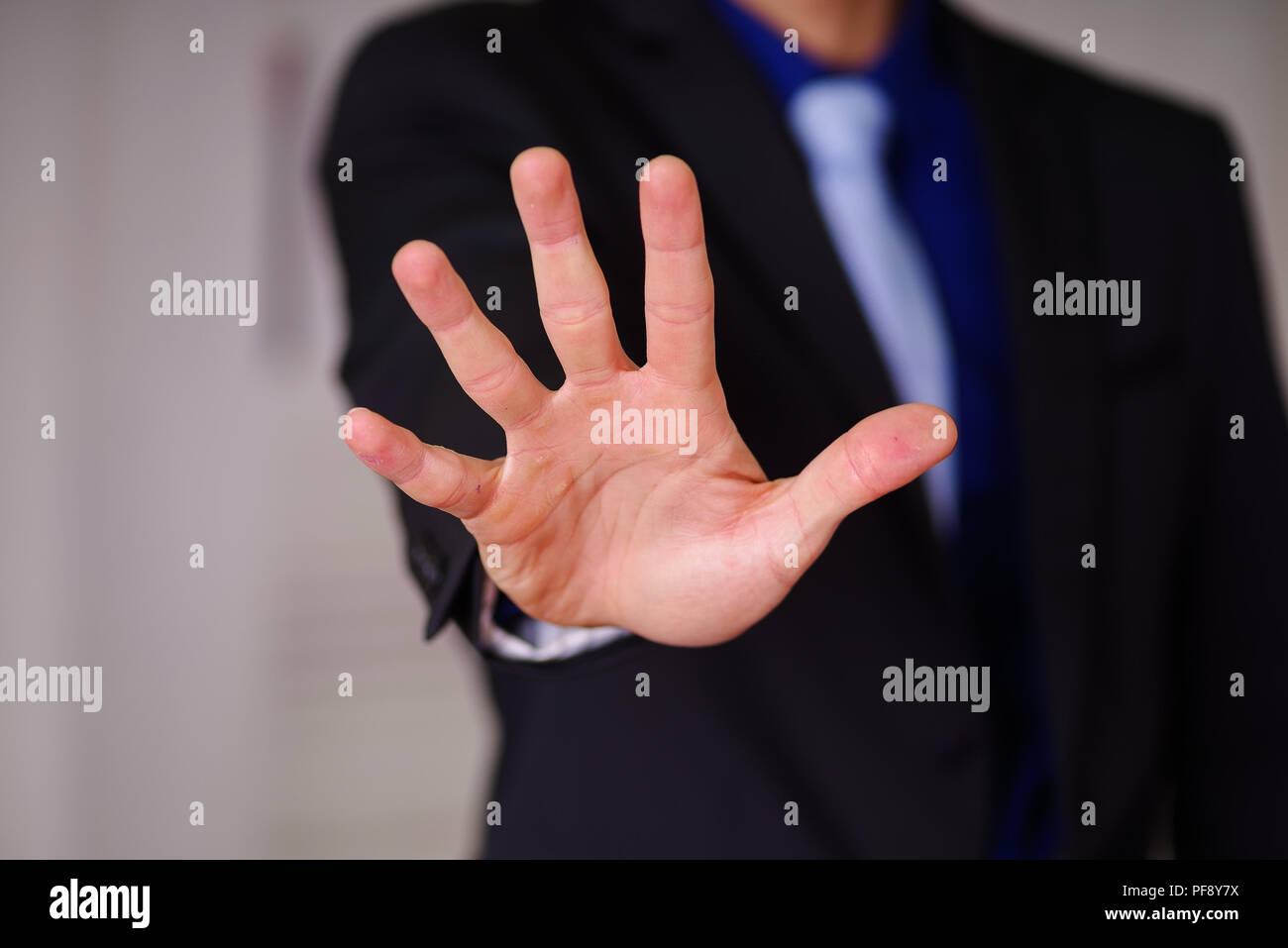 Close up of man wearing a suit with his open hand pointing in front of ...