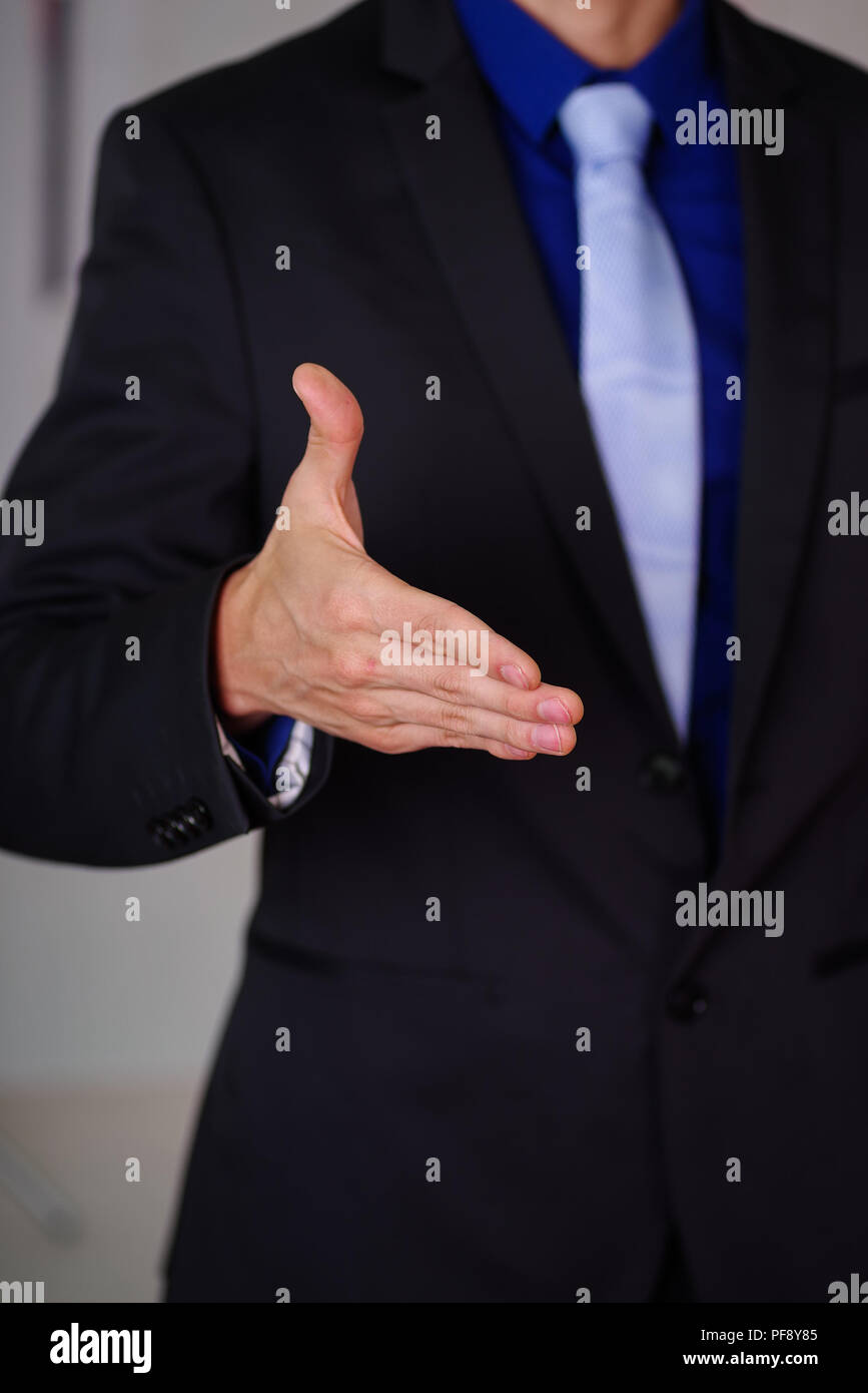 Close up of man wearing a suit with his open hand in front of him, in a ...