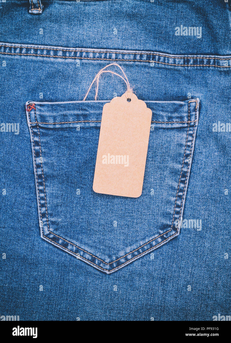fragment of blue jeans with a brown paper empty tag on a rope, full ...