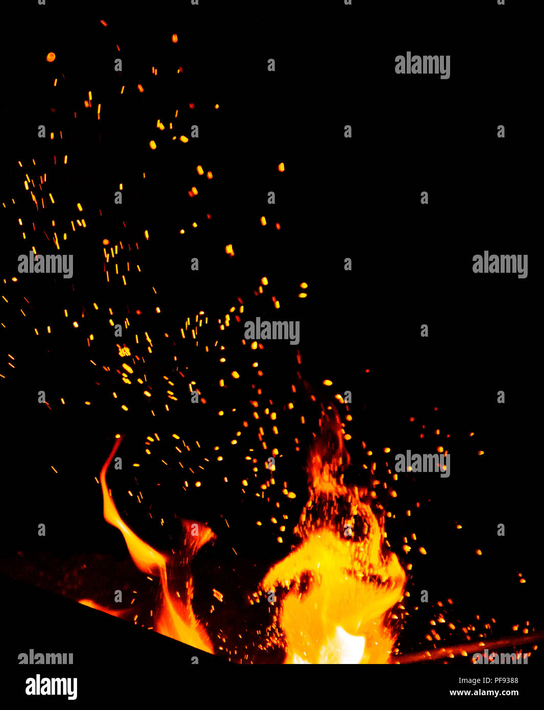 burning fire with a rising column of orange and yellow sparks on a ...