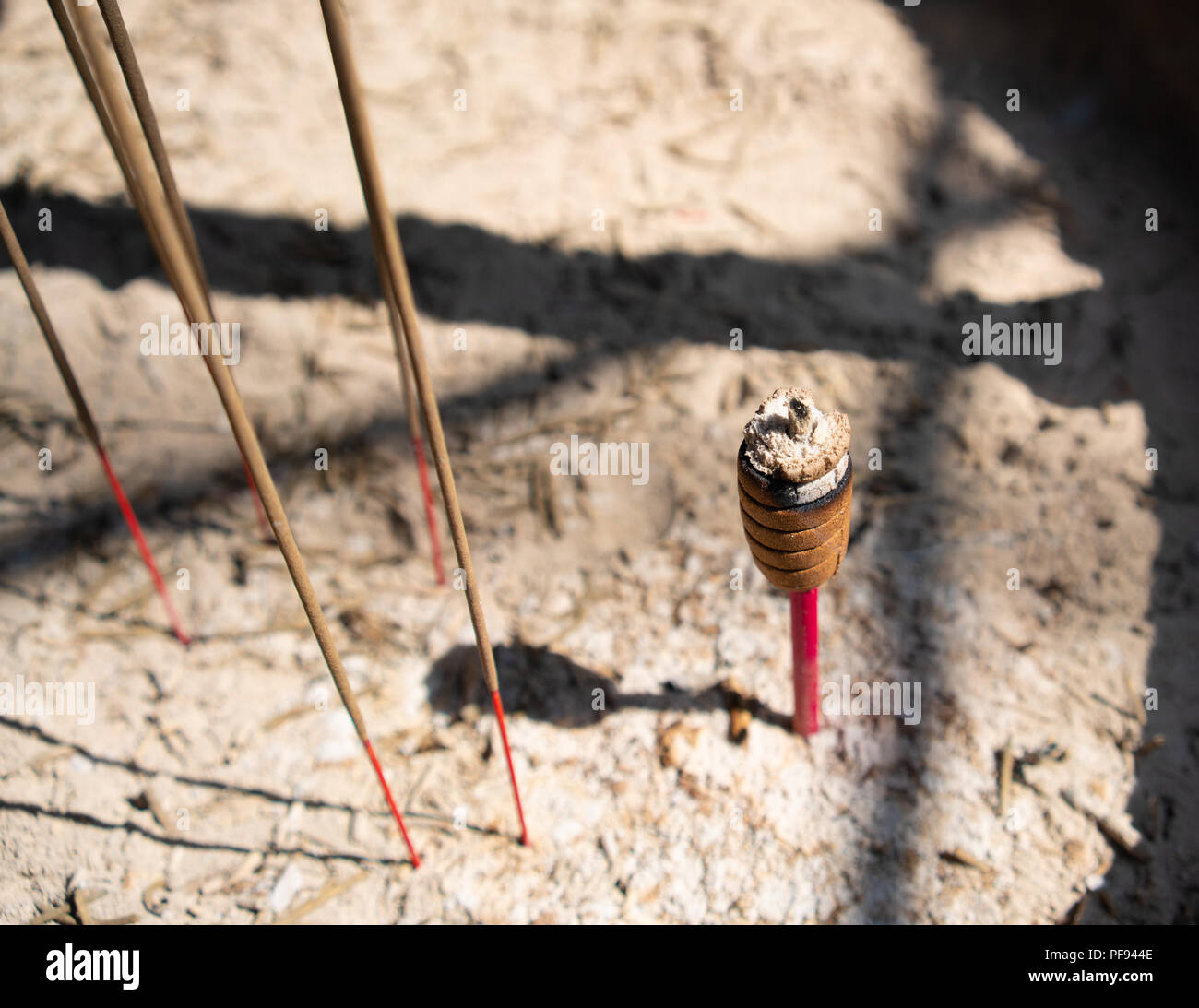 Closeup view of burning incense sticks in a censer full of sand in a ...