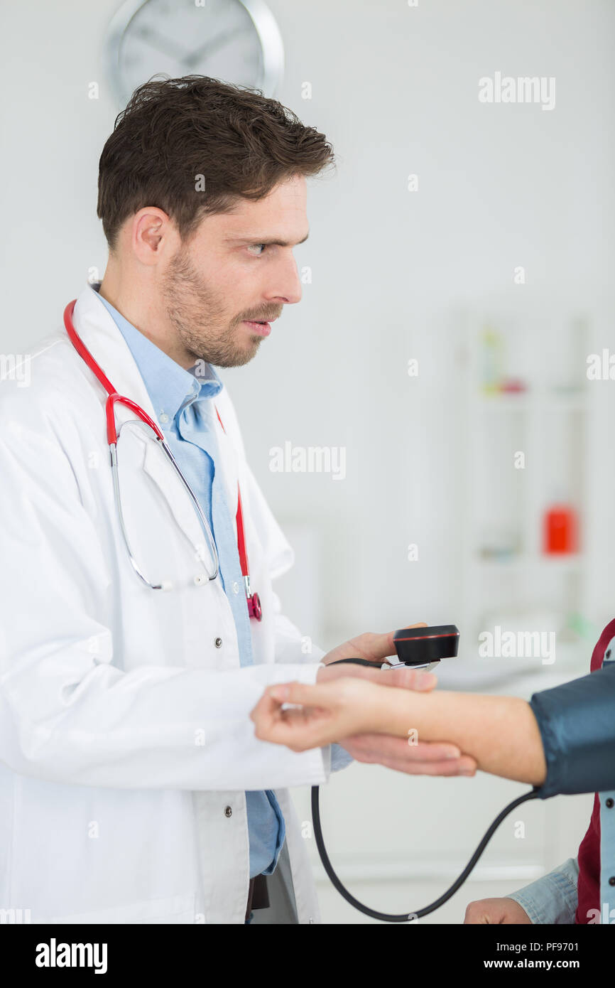 portrait of happy doctor checking patients blood pressure in clinic ...