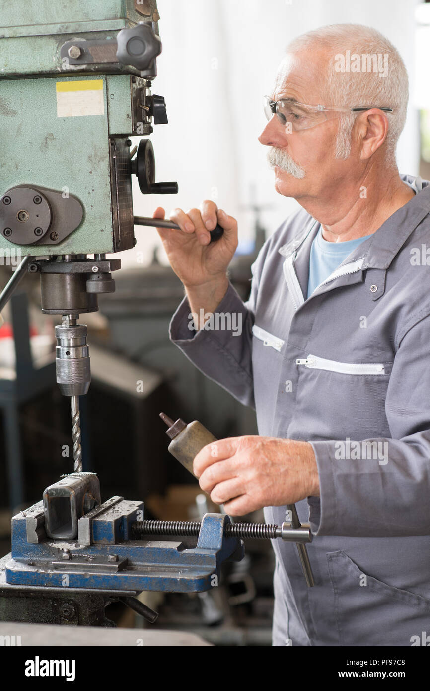 elderly worker watches processing of detail on milling machine Stock ...