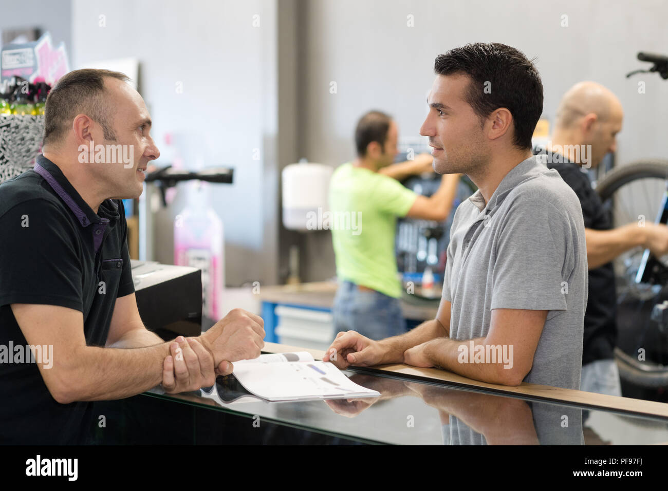 two people talking over a counter Stock Photo - Alamy