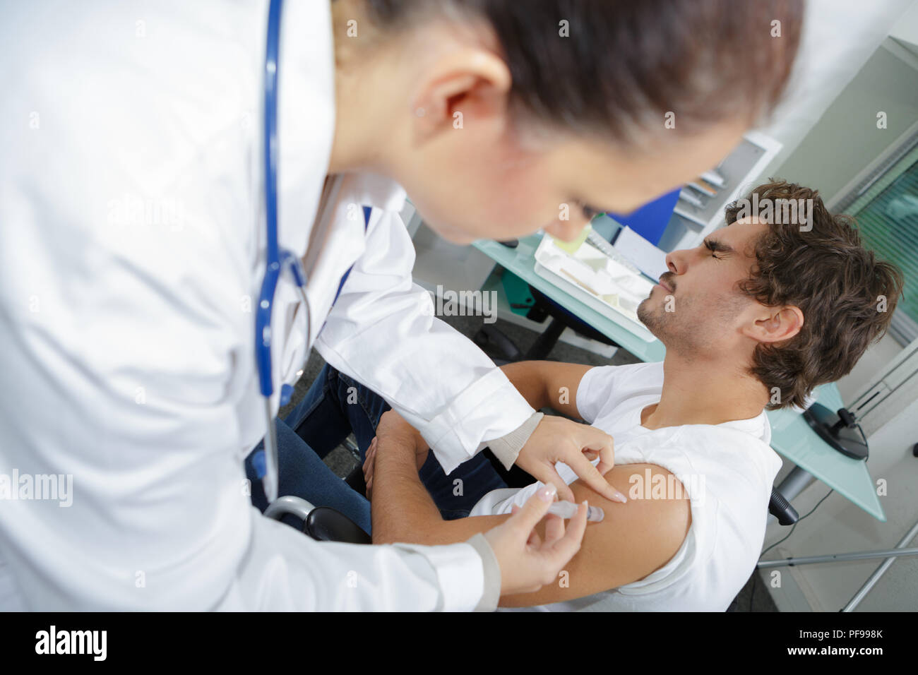 man grimacing as nurse injects him in the arm Stock Photo - Alamy