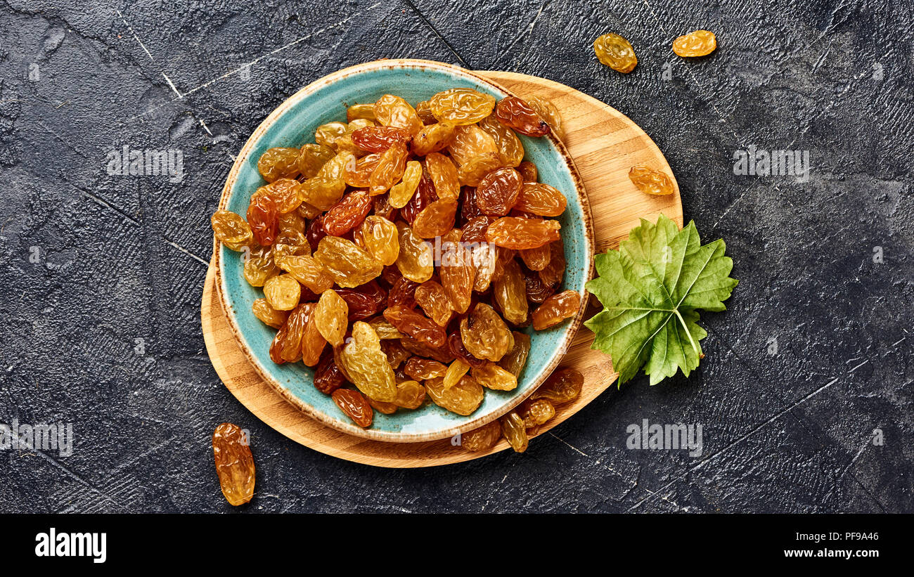 Yellow big raisins on black concrete background with copy space. Top ...