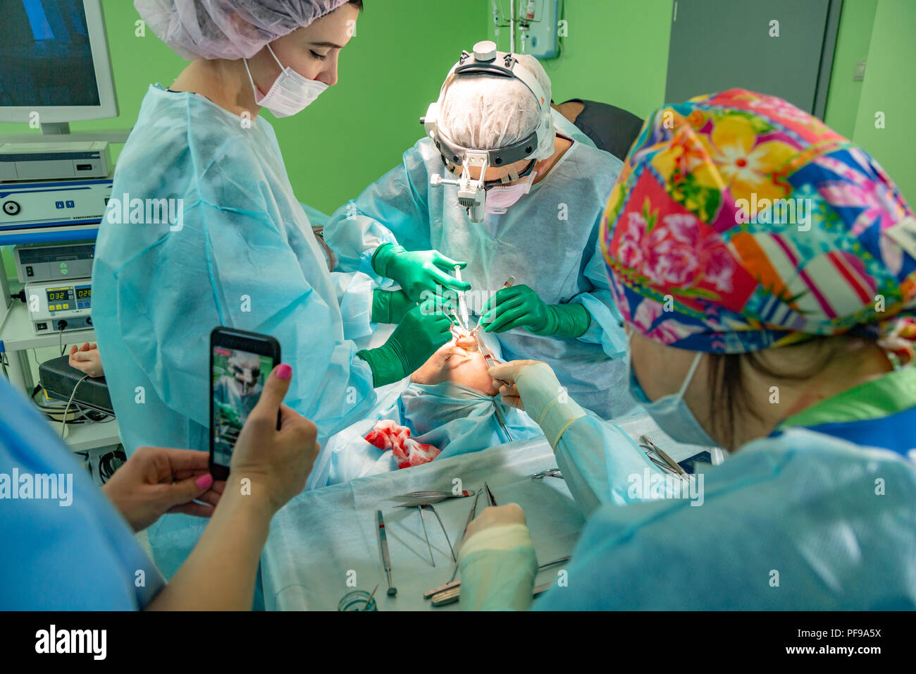 Surgeon and his assistant performing cosmetic surgery on nose in ...