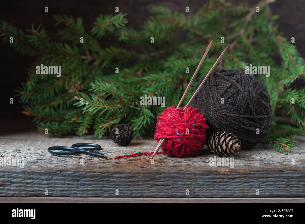 Bright red tweed wool yarn with wooden needles with a firtree ...