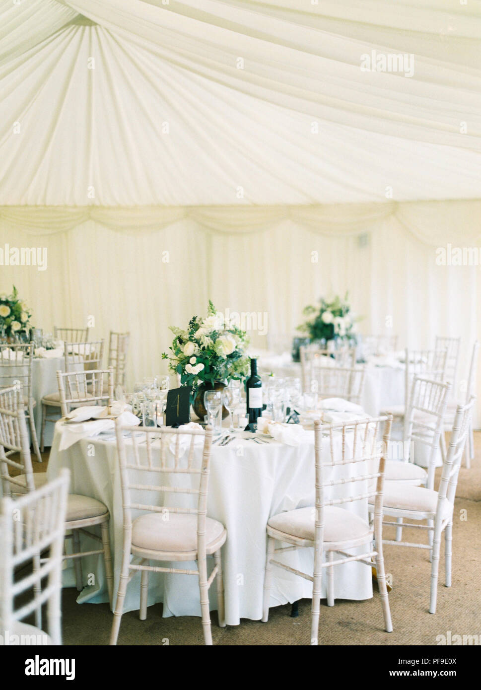 Wedding breakfast dinner place settings in a white marquee with flowers ...