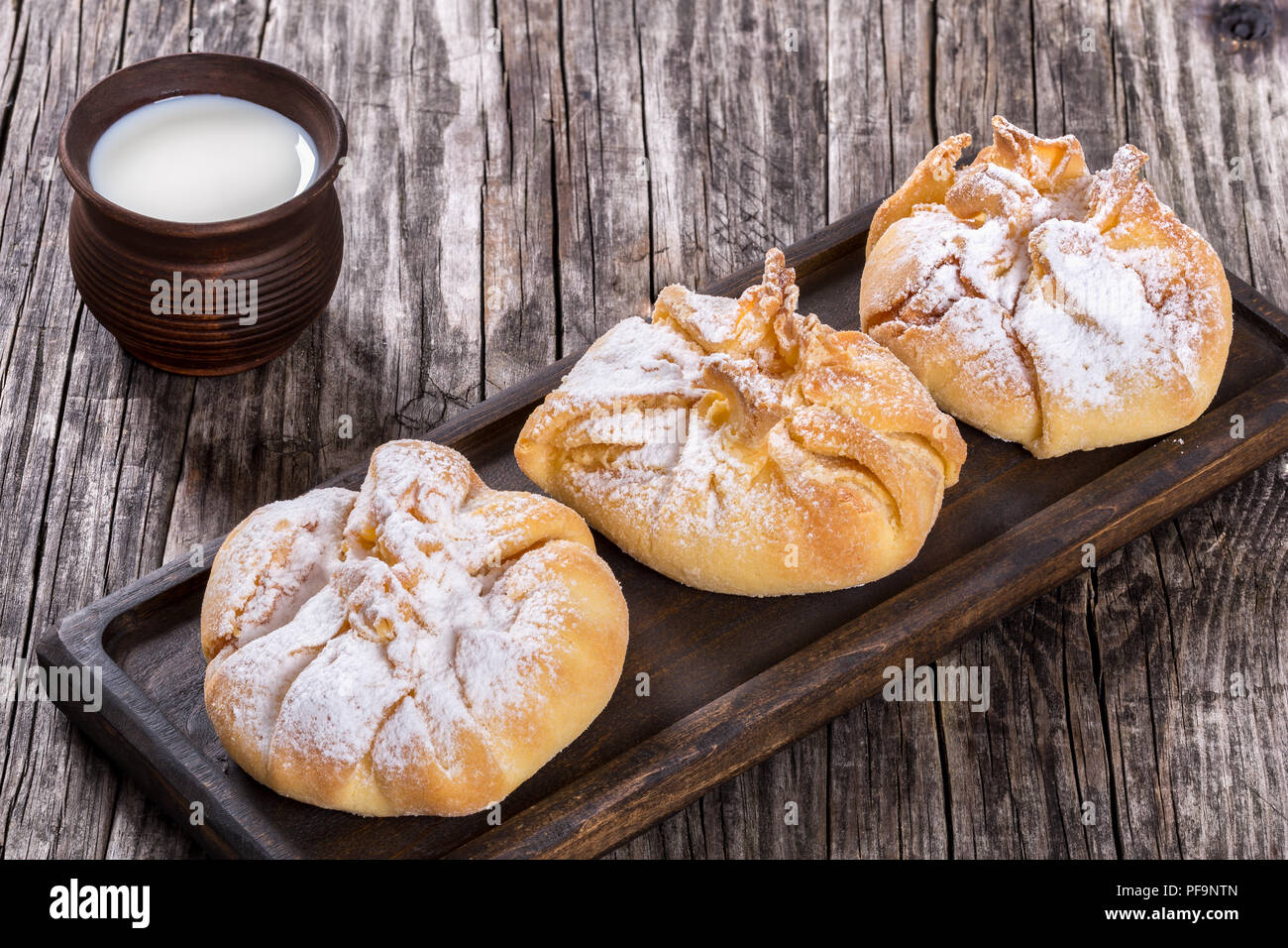 coconut puff pastries with powdered sugar dusting on a dark board on an ...