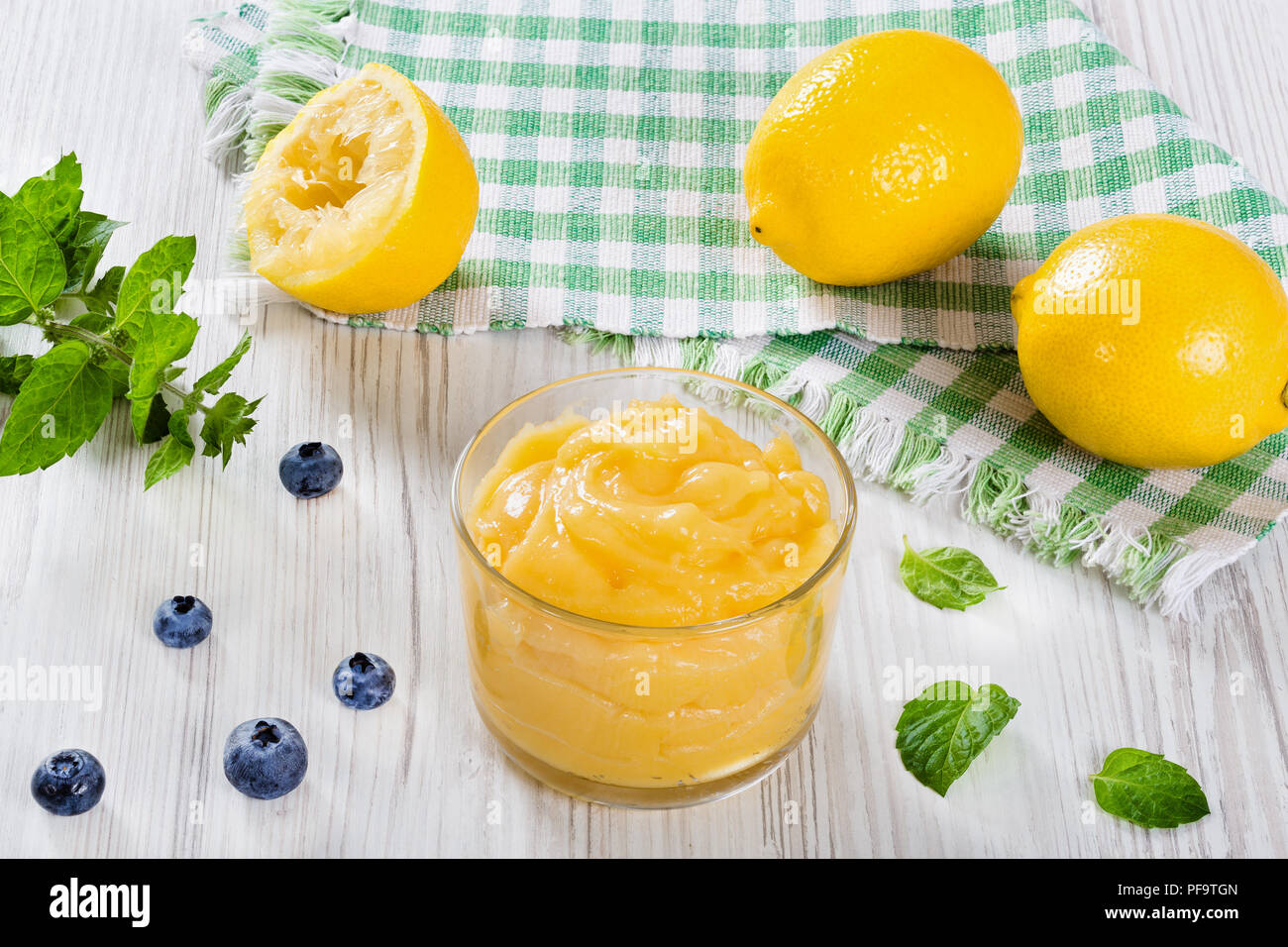 lemon curd in glass cup. blueberry and mint on white wooden planks ...