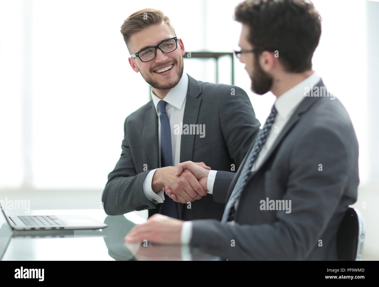 side view.handshake business partners sitting at the Desk Stock Photo ...