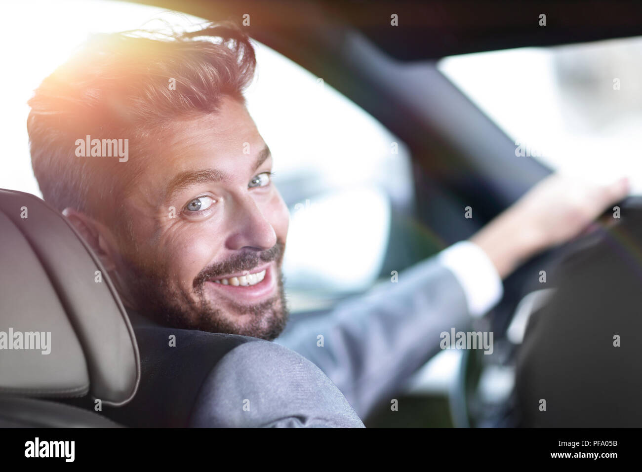 rear view, young man driving his car, looking at camera Stock Photo - Alamy