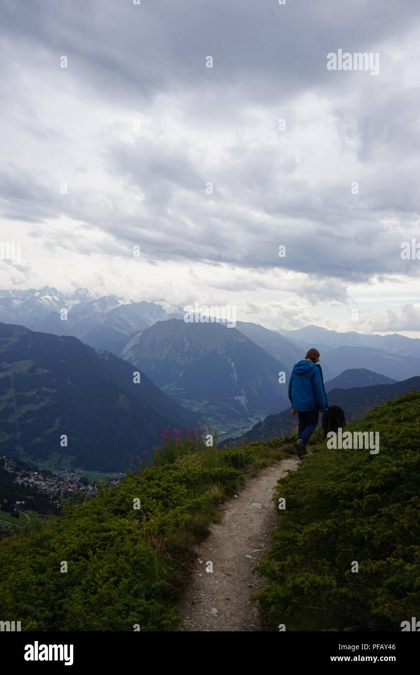 Man and a Bernese mountain Dog waking on the path in the Swiss Alps ...