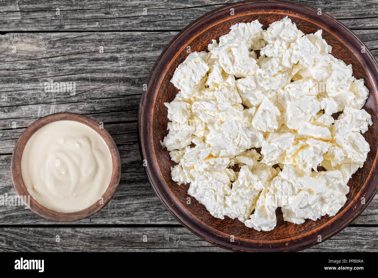 organic cottage cheese on a clay plate, sour cream in a small bowl on ...