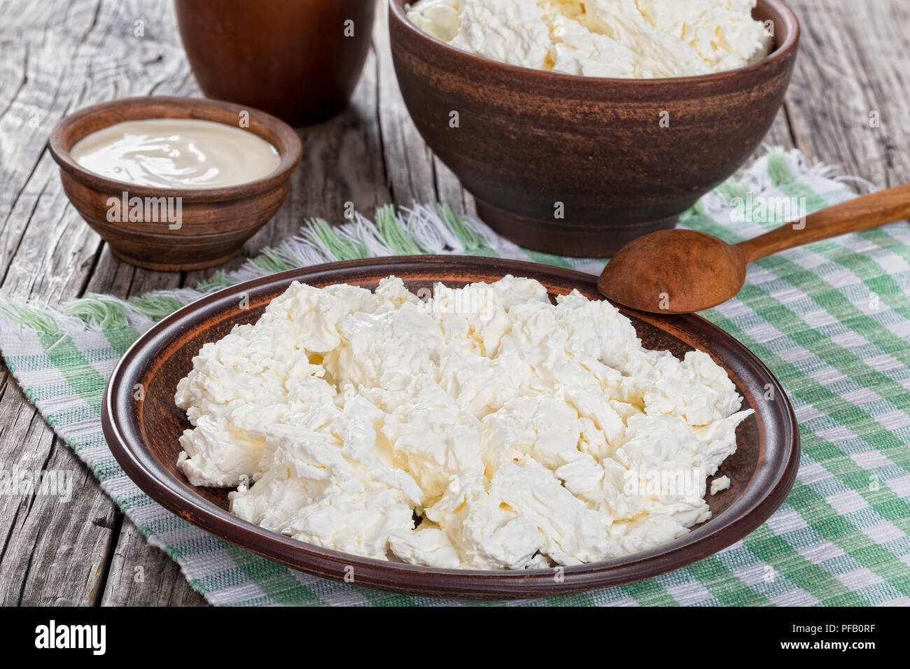 cottage cheese on clay dish with wooden spoon on kitchen tablecloth ...