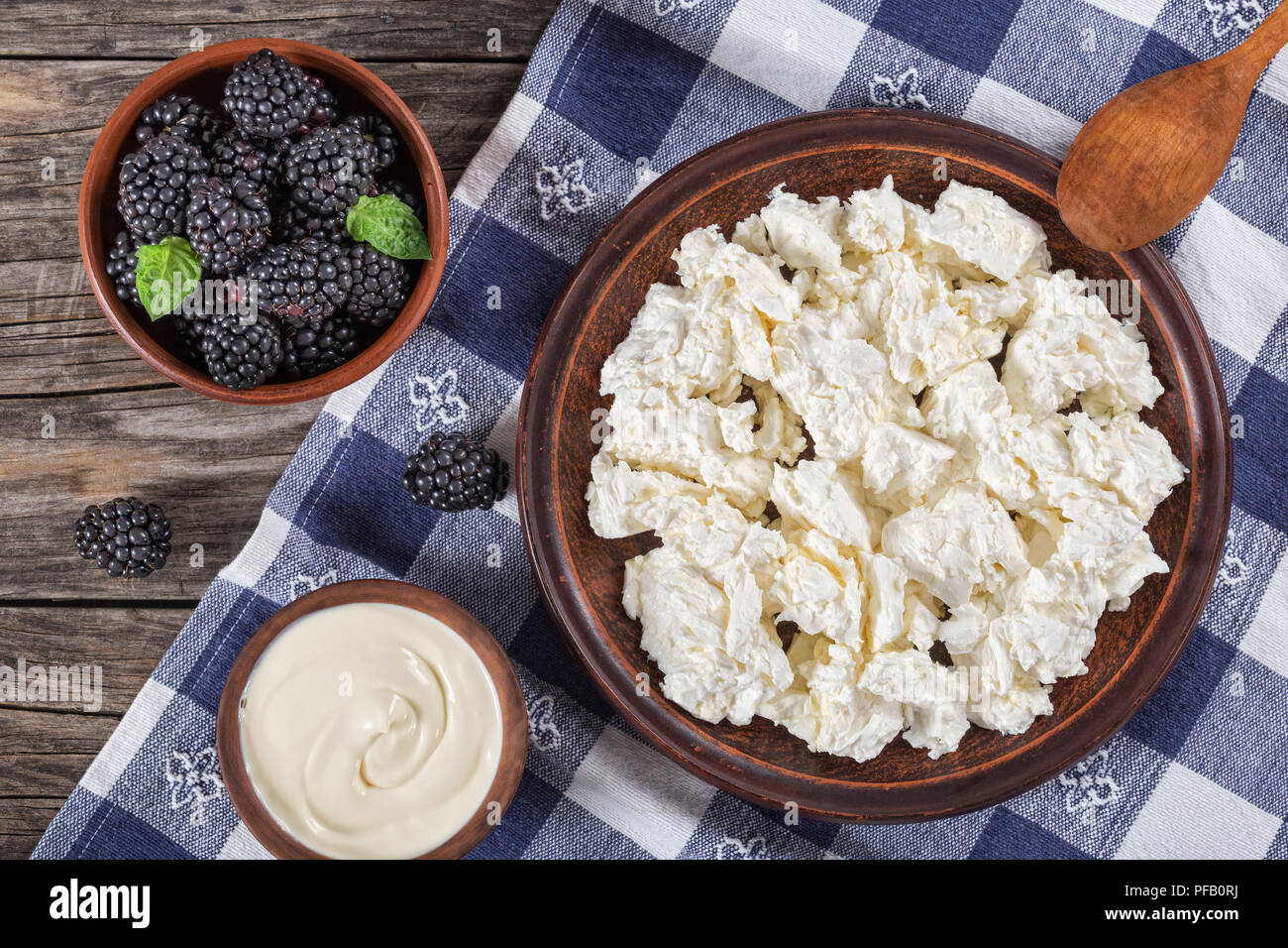 Fresh organic cottage cheese on clay dish and in pot, on kitchen towel ...