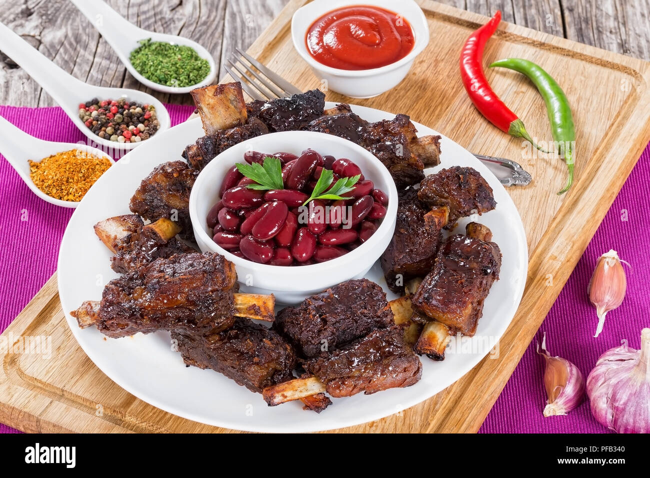red beans in a bowl surrounded by grilled ribs on dish on cutting board ...