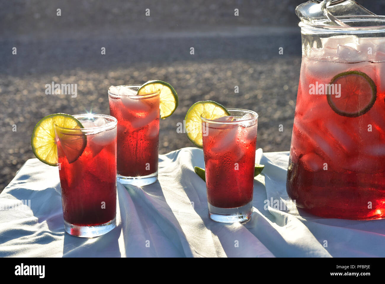 red colorful hibiscus flower iced tea cold drink in glasses and pitcher ...