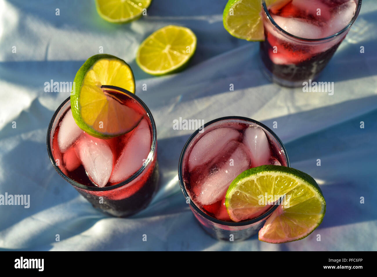 red colorful hibiscus flower iced tea cold drink in glasses and pitcher ...