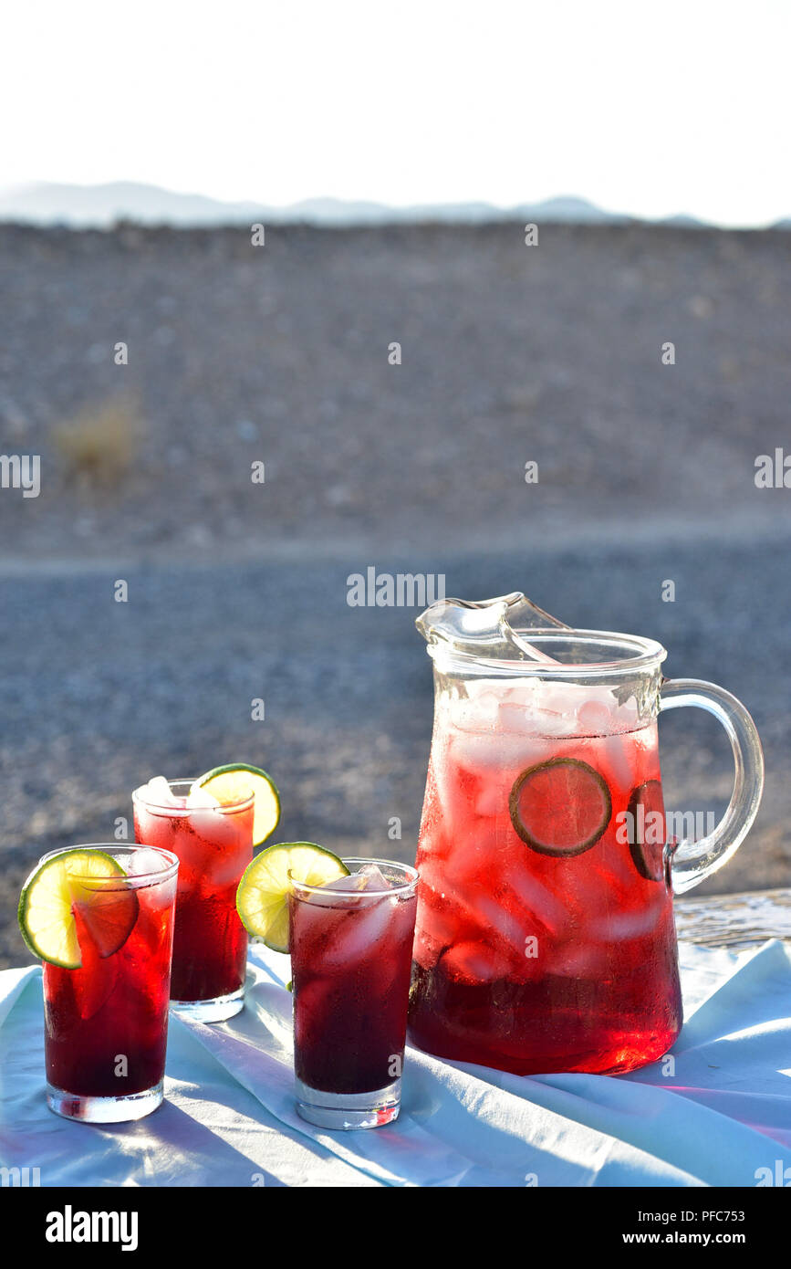 red colorful hibiscus flower iced tea cold drink in glasses and pitcher ...