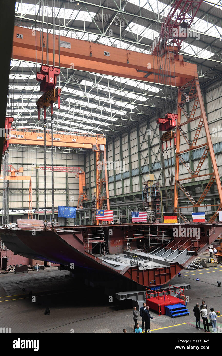 Stralsund, Germany. 21st August, 2018. Shipyard workers observe a keel ...