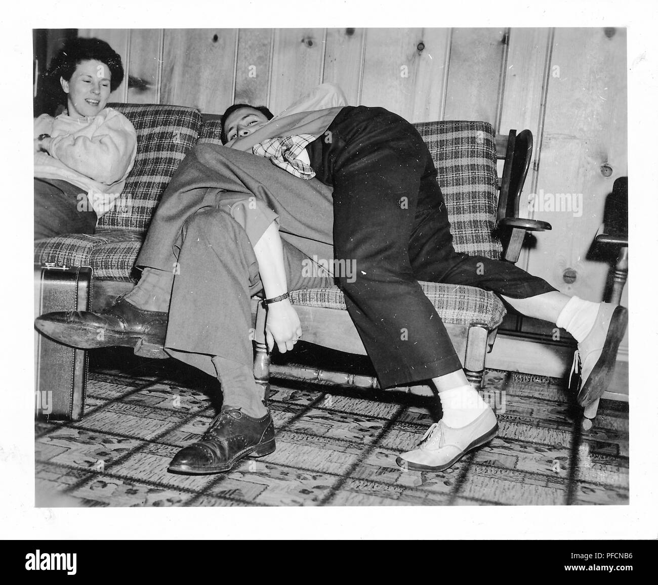 Black And White Photograph Showing Several People On A Plaid Couch A