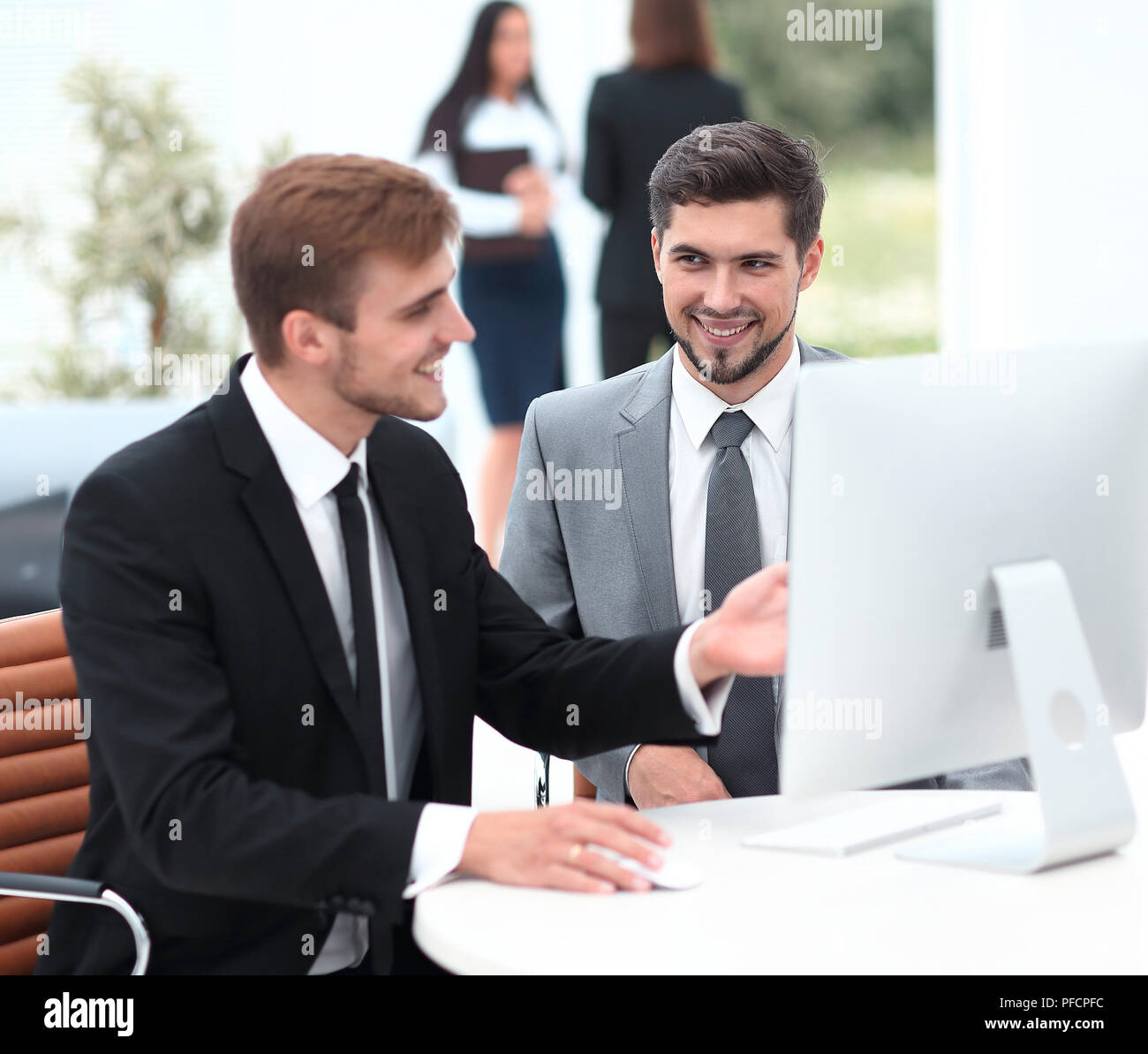 employees are talking sitting behind a Desk Stock Photo - Alamy