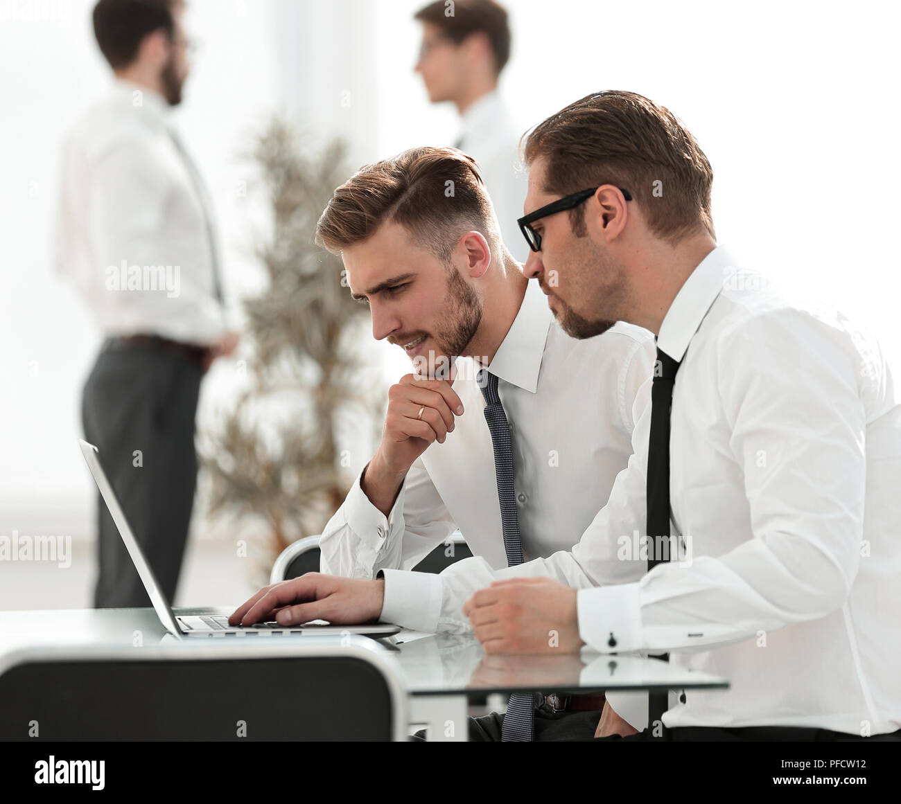 two employees use a laptop to check data Stock Photo - Alamy