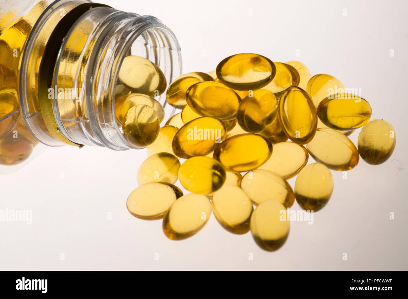 Fish oil capsules spilling from bottle on white background Stock Photo ...