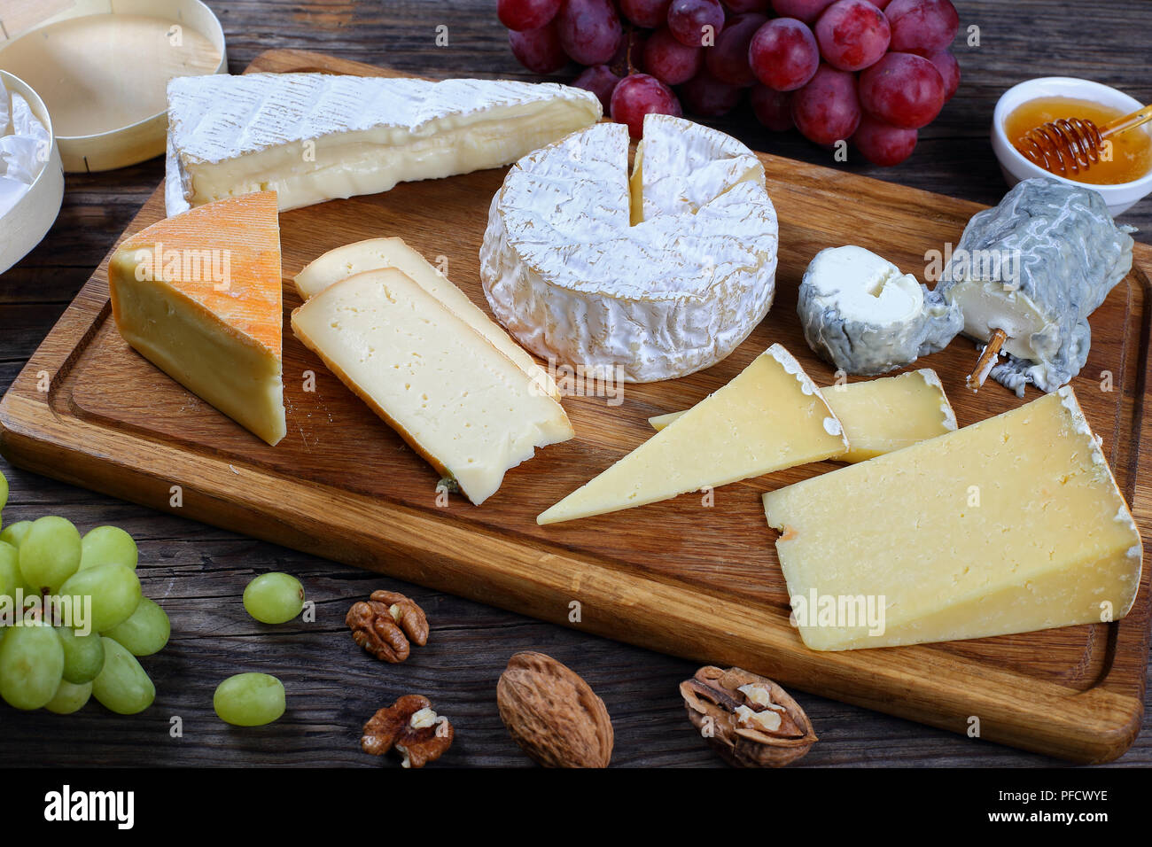 set of authentic french Cheeses served with grapes, honey and nuts on ...