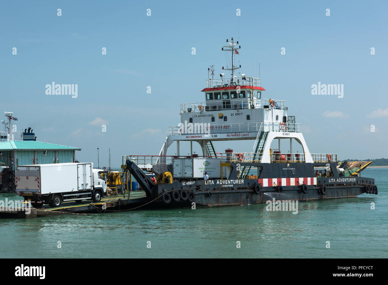 Vessel “Lita Adventurer” loading trucks at a ferry terminal in Changi ...