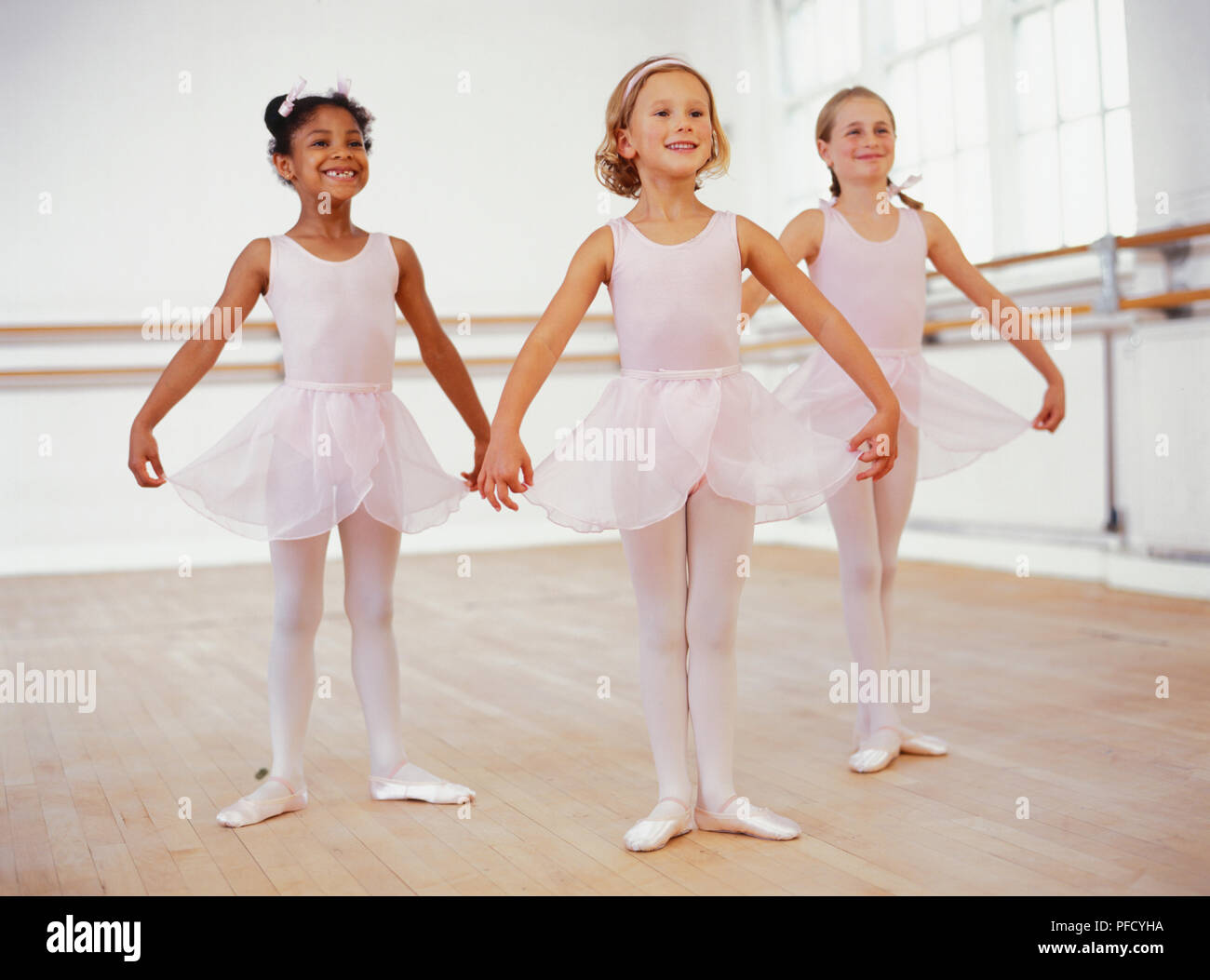 Three young ballet dancers standing straight with arms straight out to ...