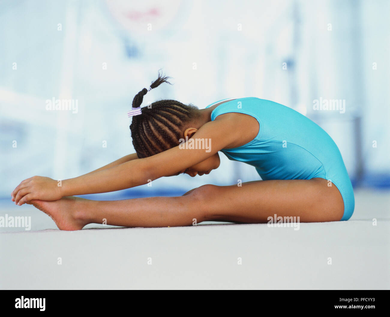 Gymnast stretching her body over legs to touch her toes Stock Photo - Alamy